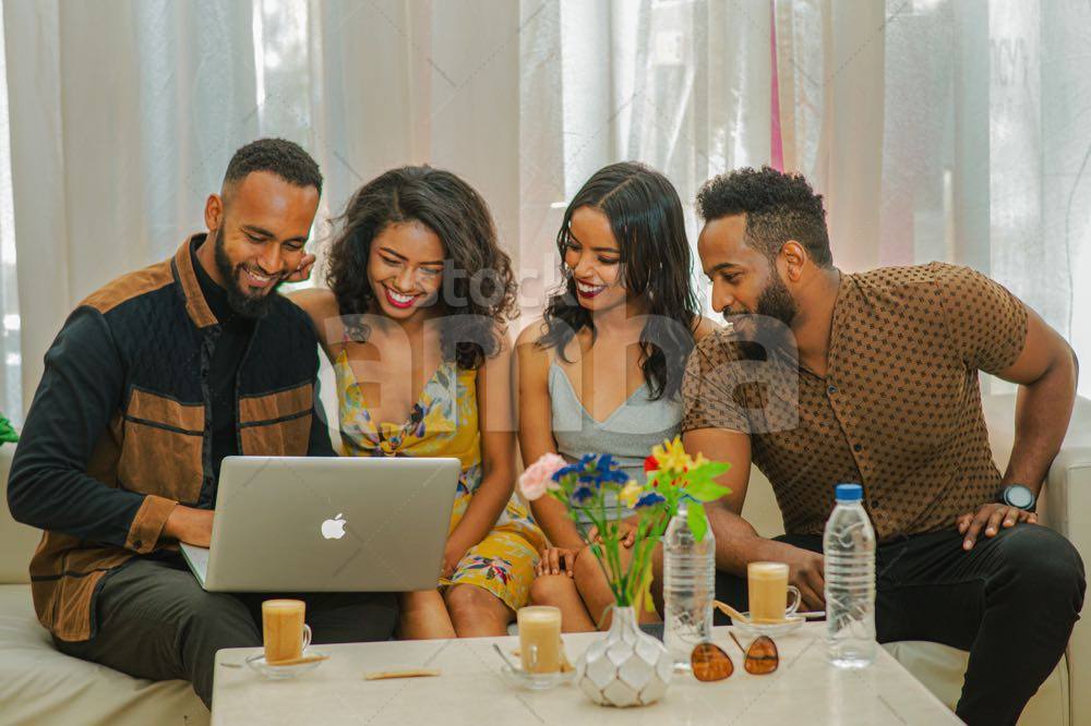 Four Friends Relaxing in Bright Room with Laptop Computer - StockAMBA.com