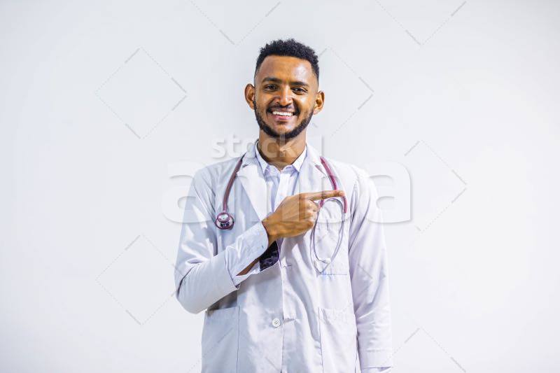 A Doctor Wearing White Coat with Stethoscope Pointing Aside with Index ...